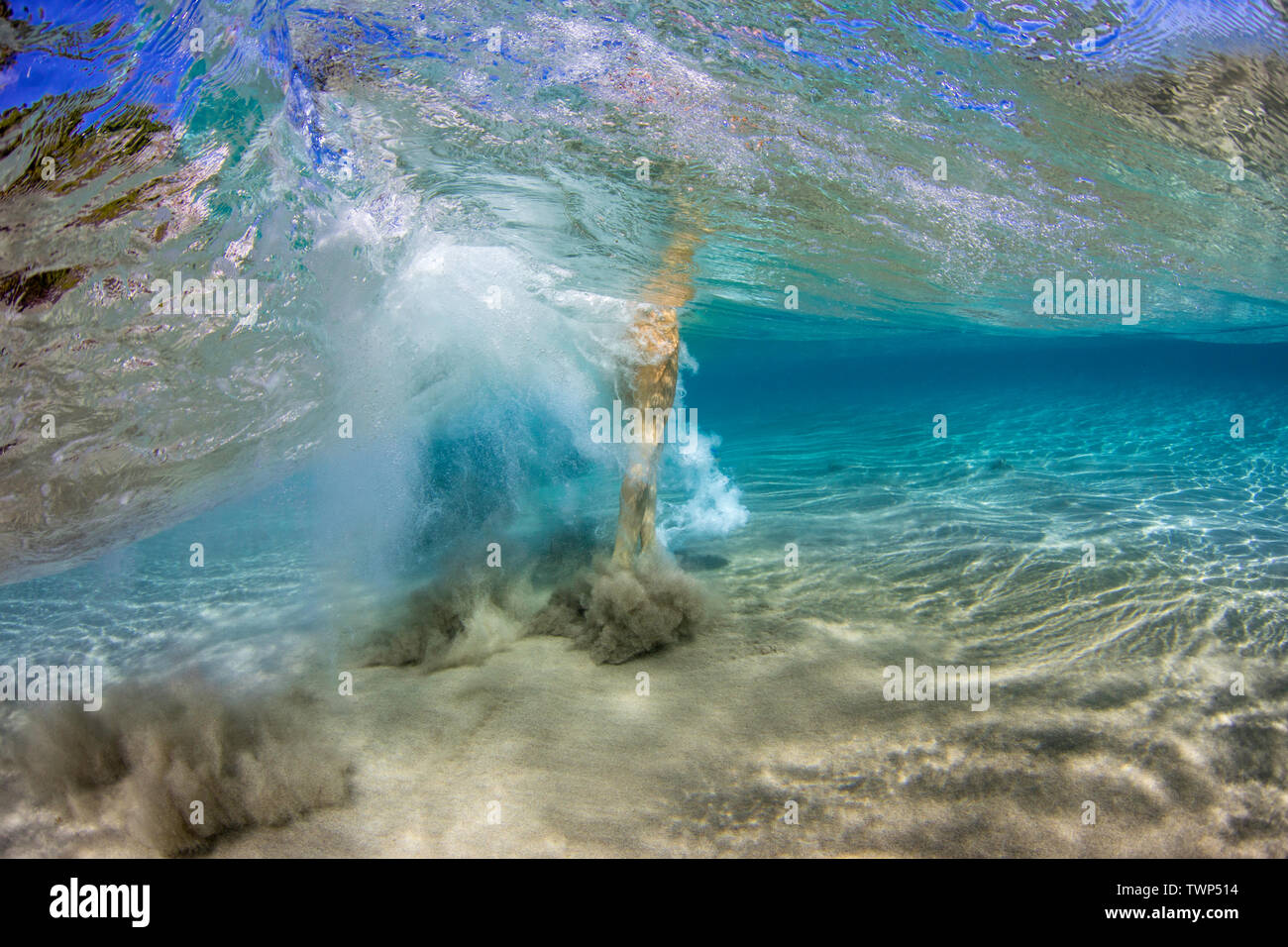 Surf crashes around a young lady (MR) walking across a sandy bottom off ...