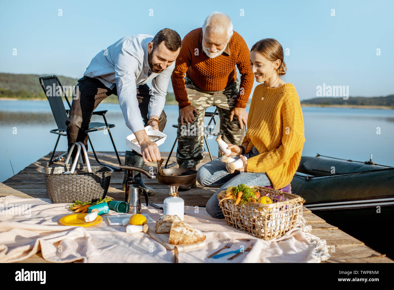Man and woman with senior grandfather having a picnic with vegetables ...