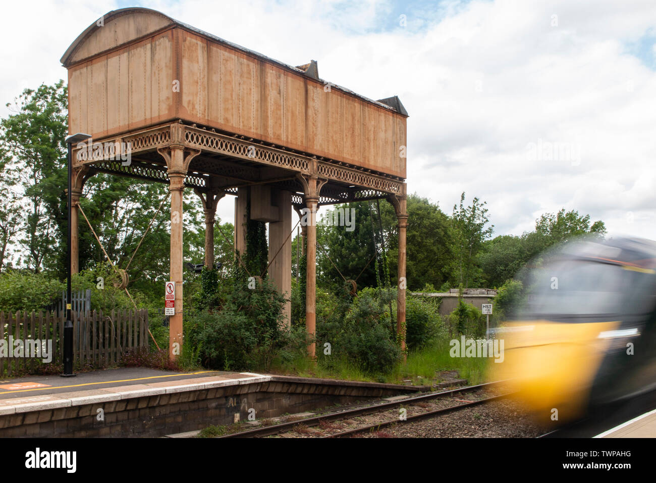 A modern Great Western train passes a Victorian water tower at Kemble ...