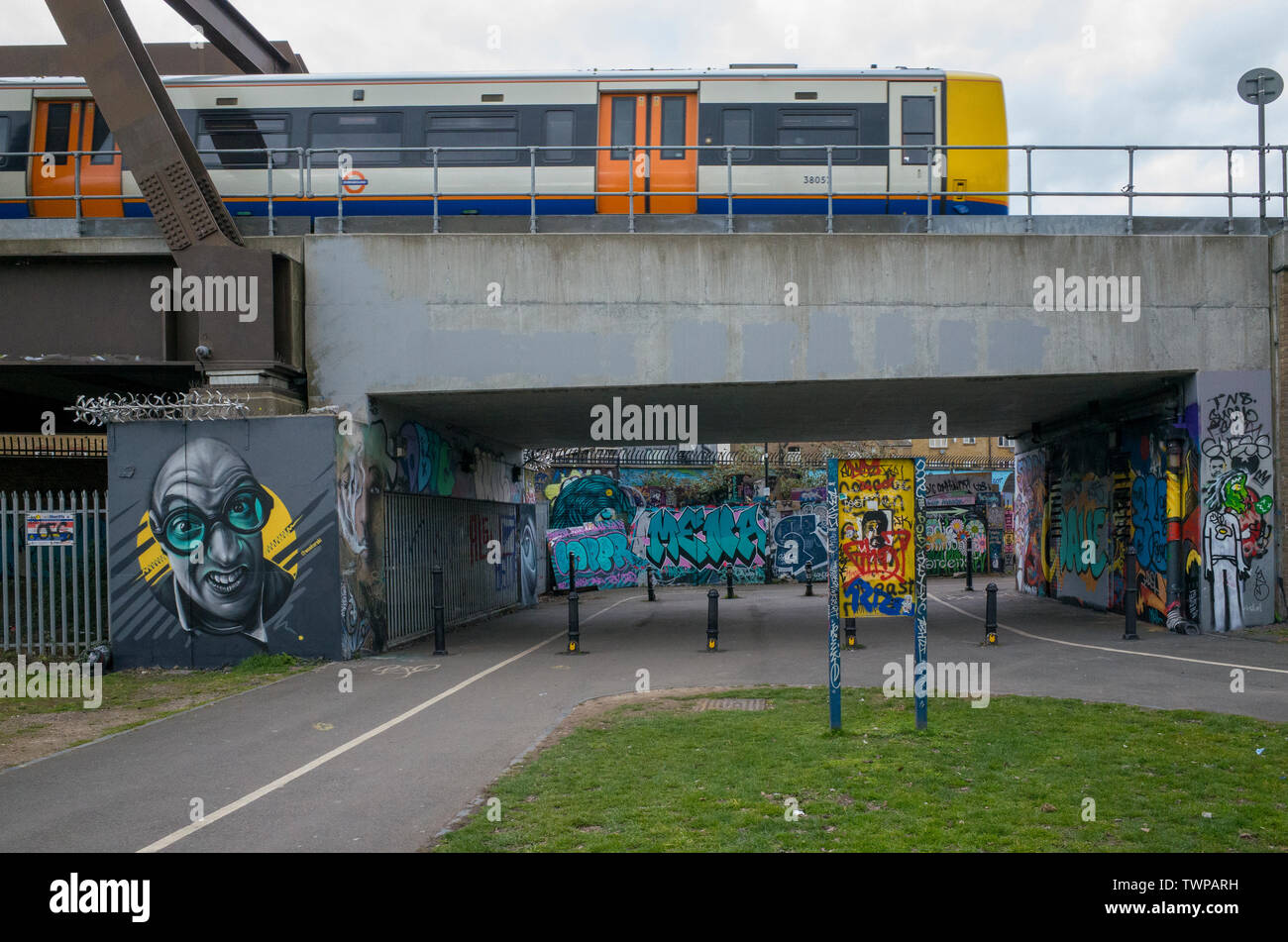 A London Overground train passes over a bridge on Pedley Street showing ...