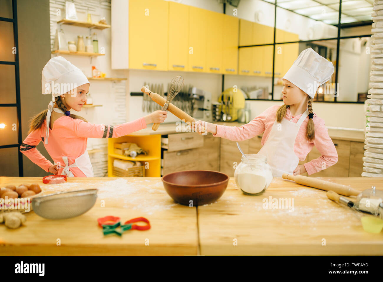 Two girls cooks in caps fights on the kitchen Stock Photo - Alamy