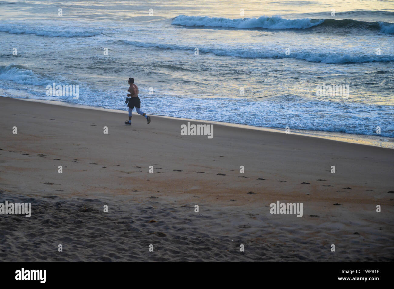 Duck, North Carolina, USA -- June 10, 2019. A man in shorts is running ...