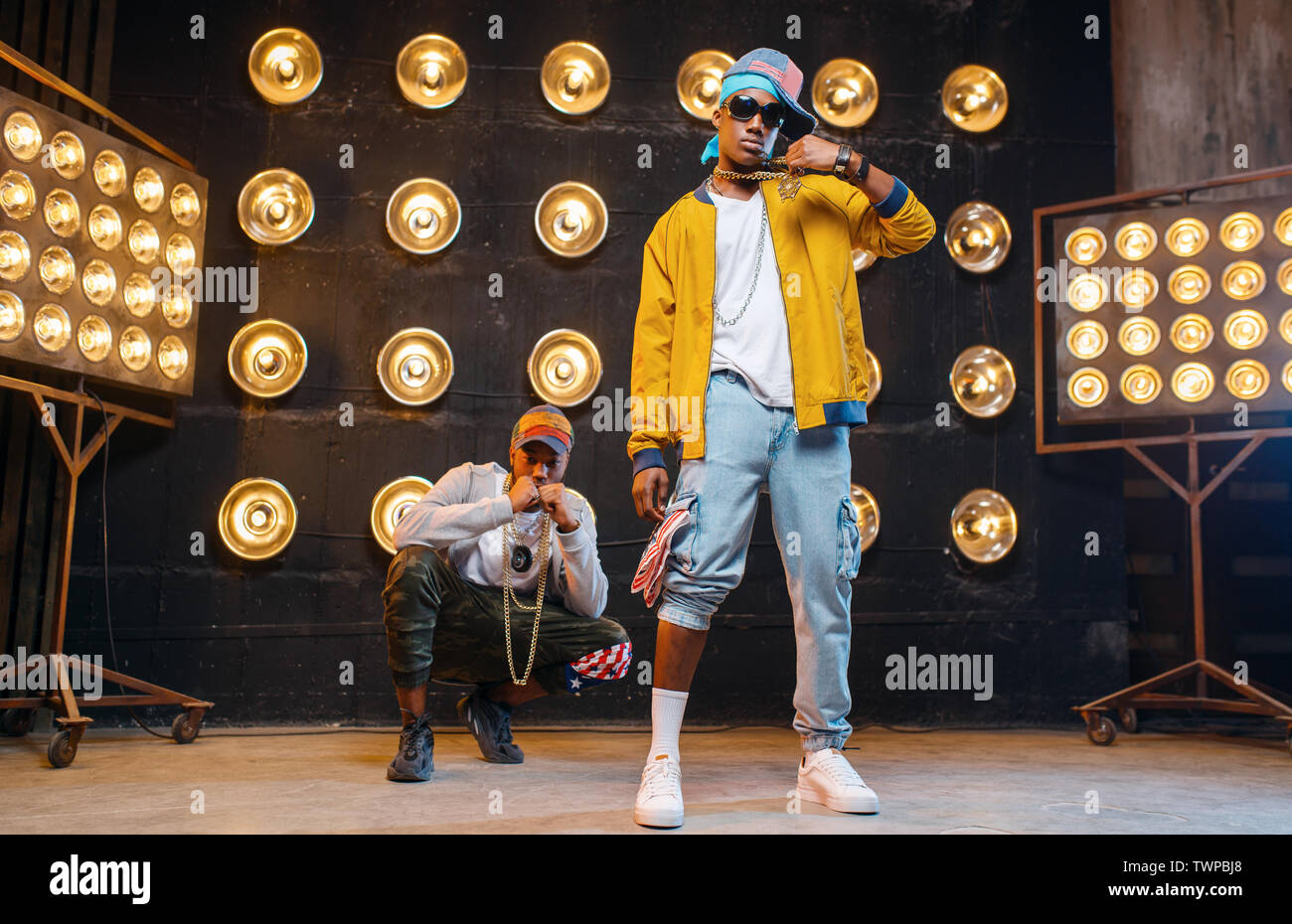 Rappers in caps dance on stage with spotlights Stock Photo - Alamy