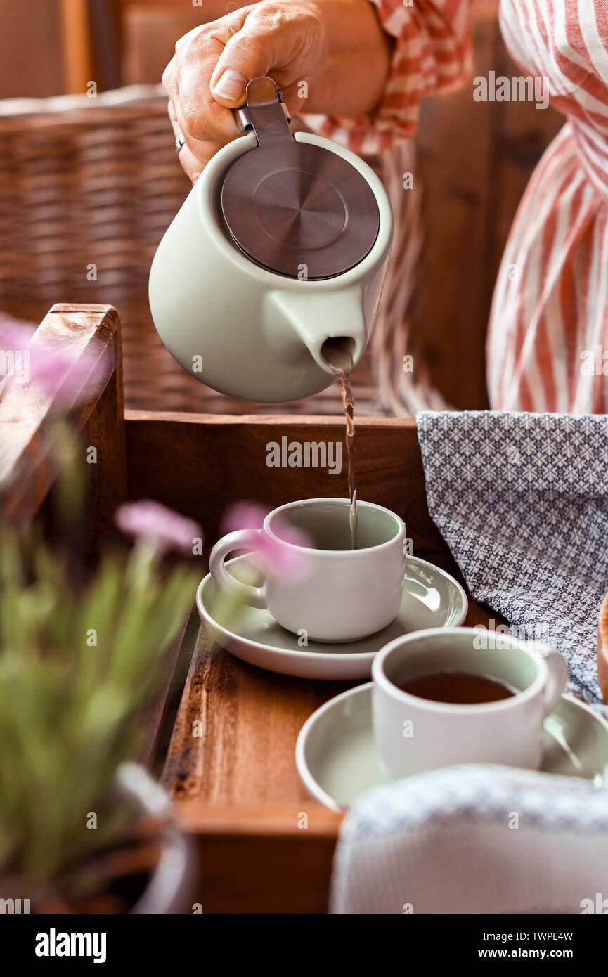 A woman pours tea into a mug of tea. Cozy atmosphere and homemade ...