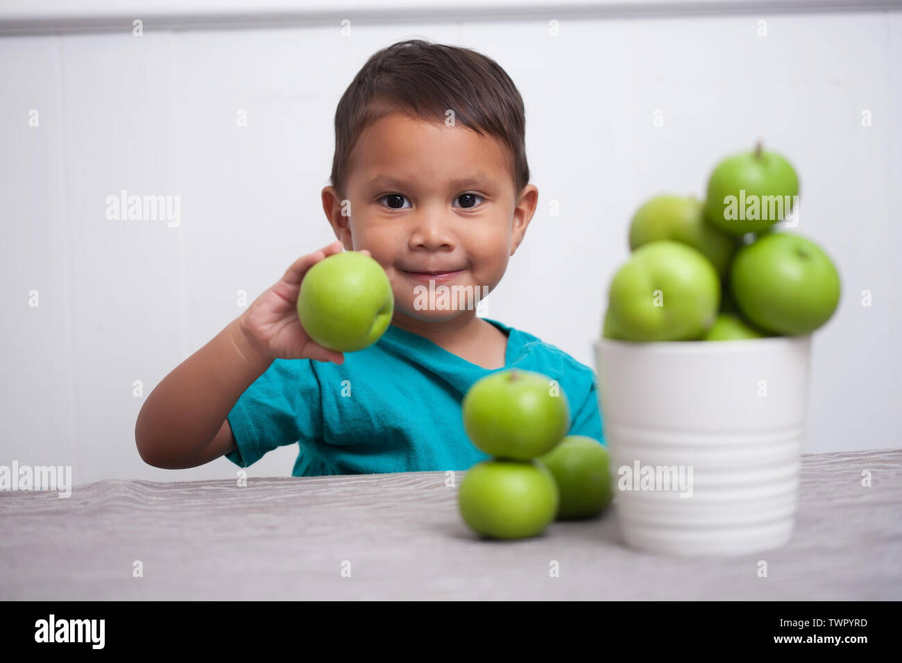 A toddler happy to be holding a green apple from his hand picked pile ...