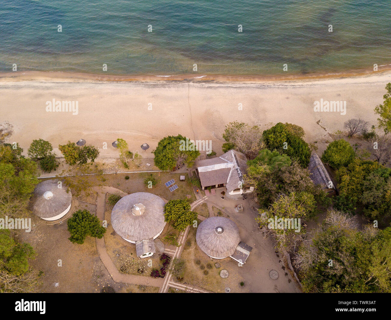 Aerial view of a resort with thatched chalets with the lake in the ...