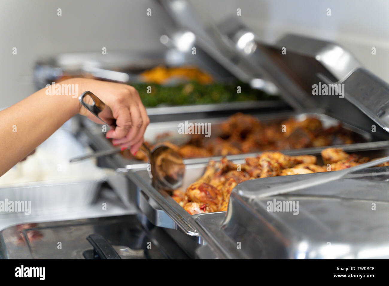 Nigerian African American Woman filling chaffing Dish with food at ...