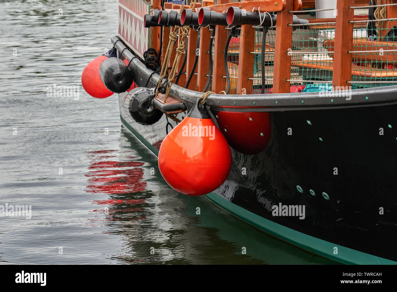 side of a black commercial fishing boat with bright orange floats ...