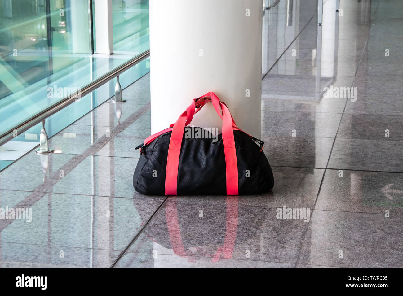 Suspicious black and red bag left unattended in an empty hall. Concept ...