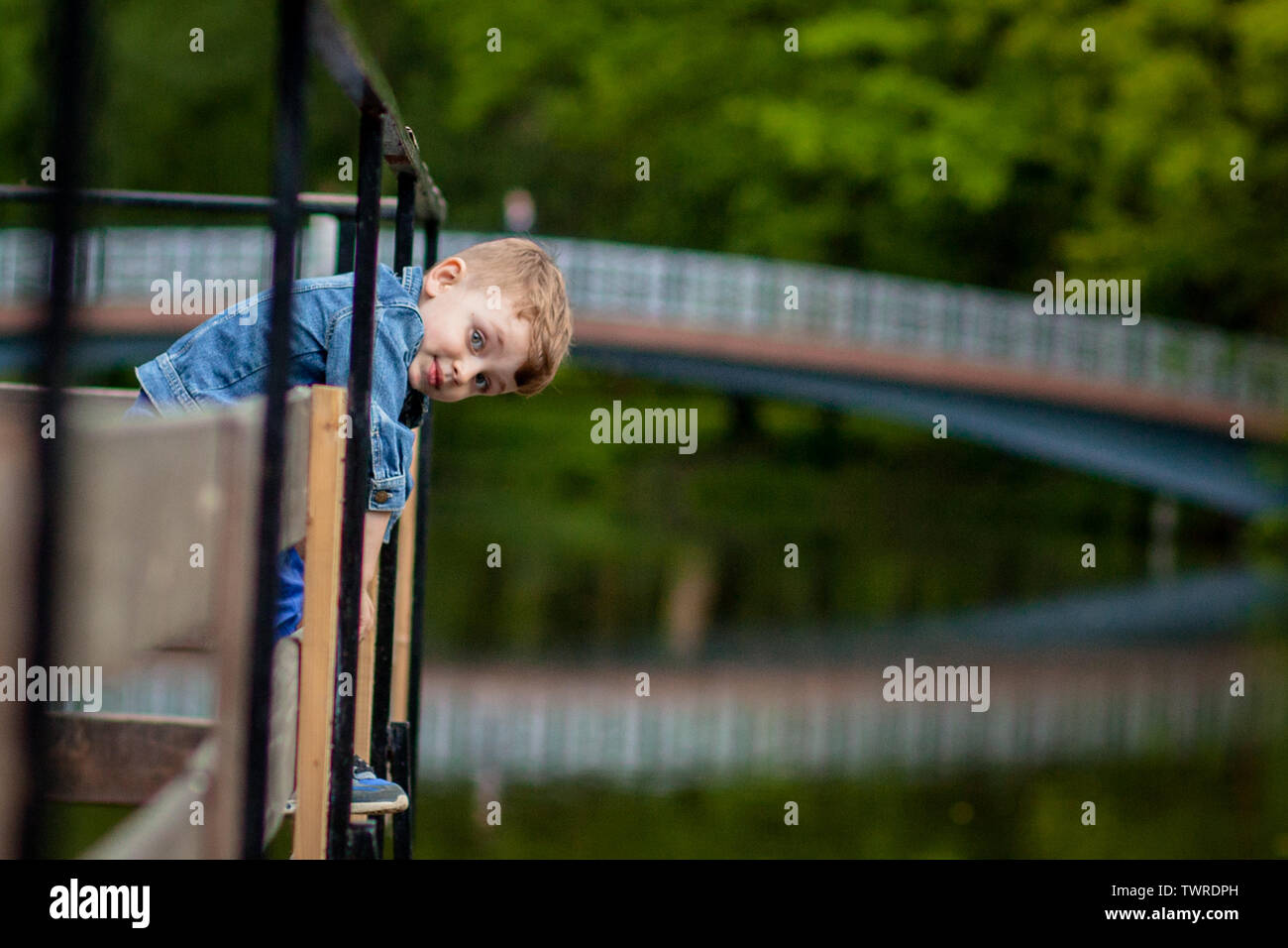 A little boy climbs a bridge railing in the park. The threat of ...