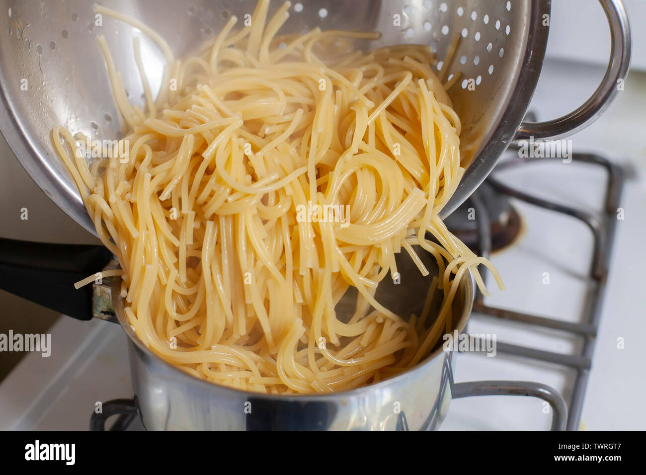 Pouring cooked and drained spaghetti into a boiling pot Stock Photo - Alamy