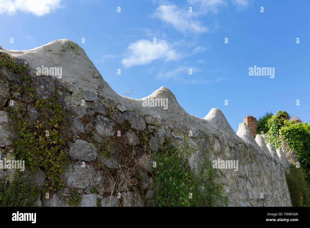 A rustic stone wall surrounds a pasture in the picturesque village of ...