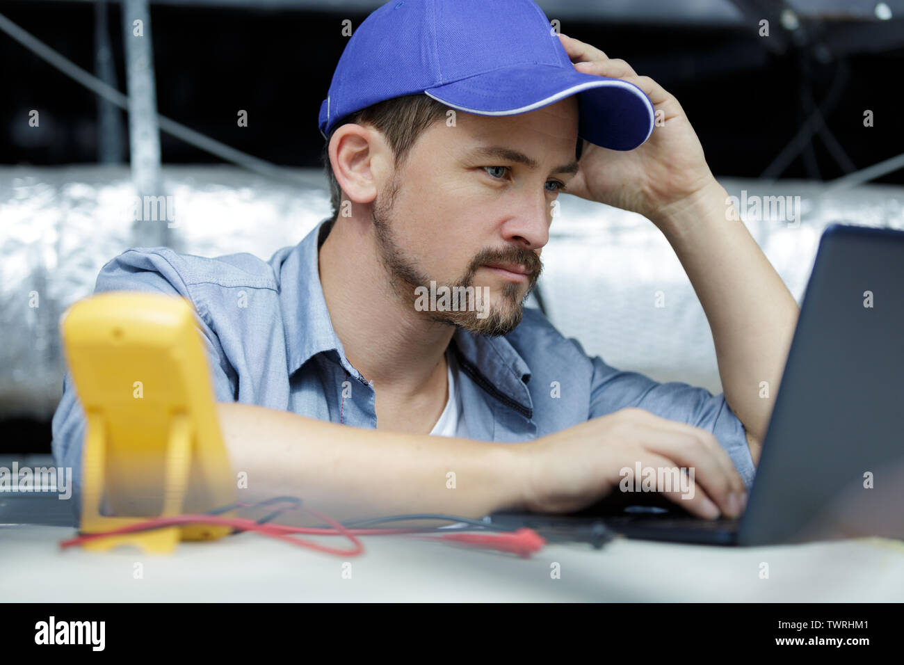 man testing electric current in circuit board of disassembled laptop ...