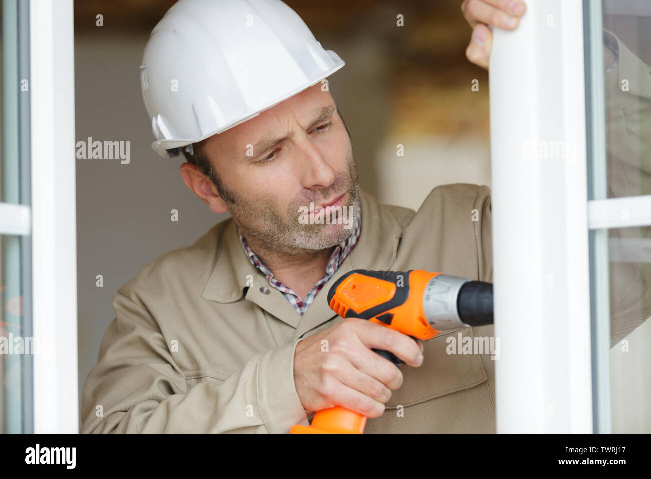 man drilling a hole in a window frame Stock Photo - Alamy