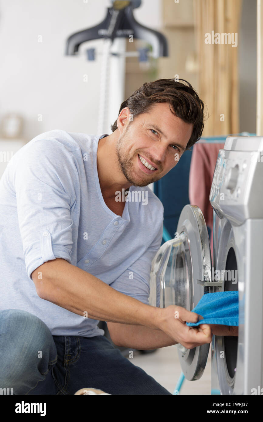 man putting color clothes into washing machine Stock Photo - Alamy