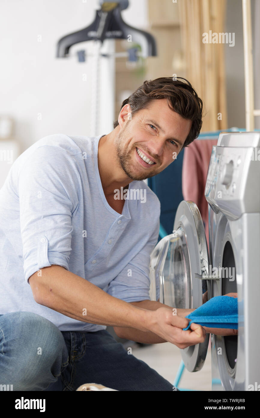 happy man loading clothes into washing machine in kitchen Stock Photo ...