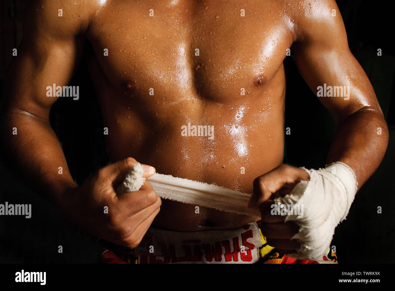 The muscular fighter tying tape around his hand preparing to fight ...