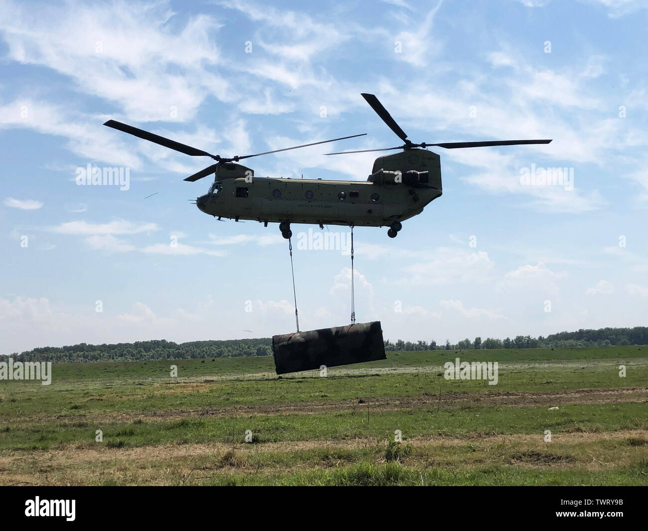 A CH-47 Chinook helicopter prepares to deliver a piece of pontoon ...