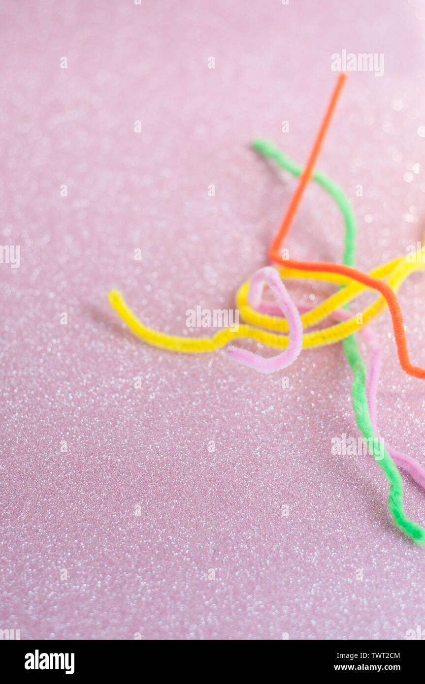 Neon colored pipe cleaners on a pink background. Messy and crumpled ...