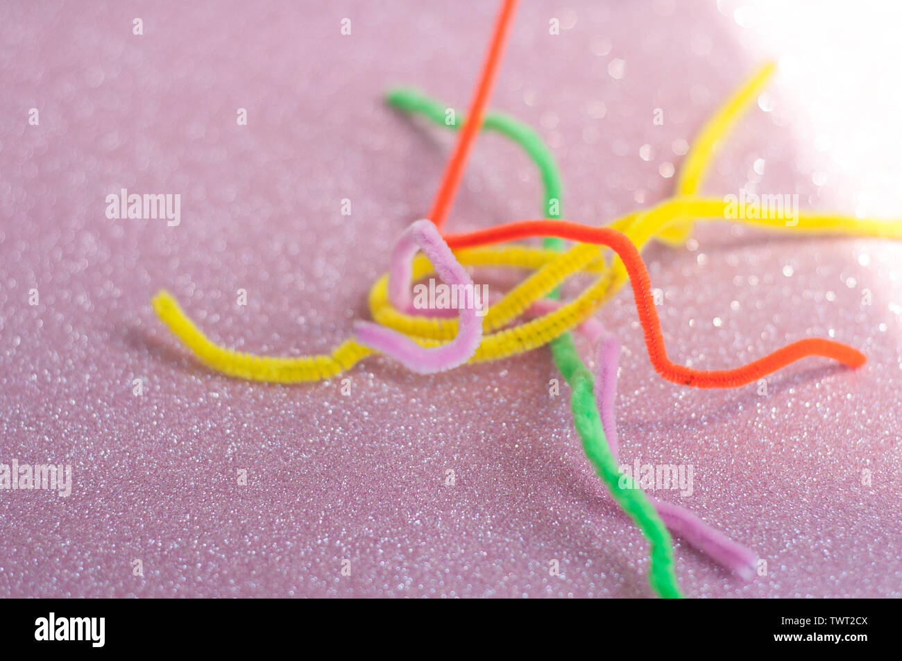 Neon colored pipe cleaners on a pink background. Messy and crumpled ...