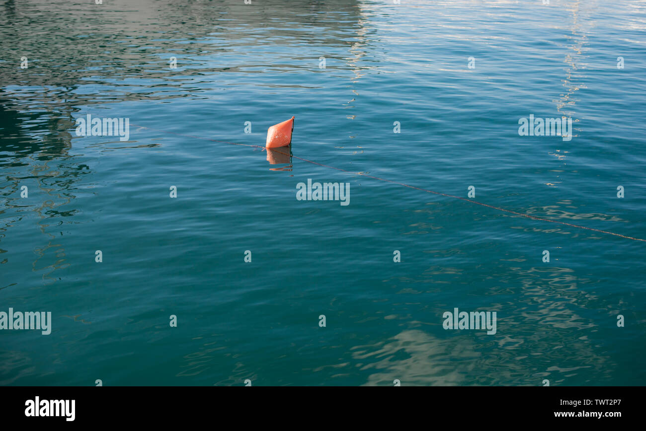 The mooring line is marked with a red cone buoy on the surface of the ...