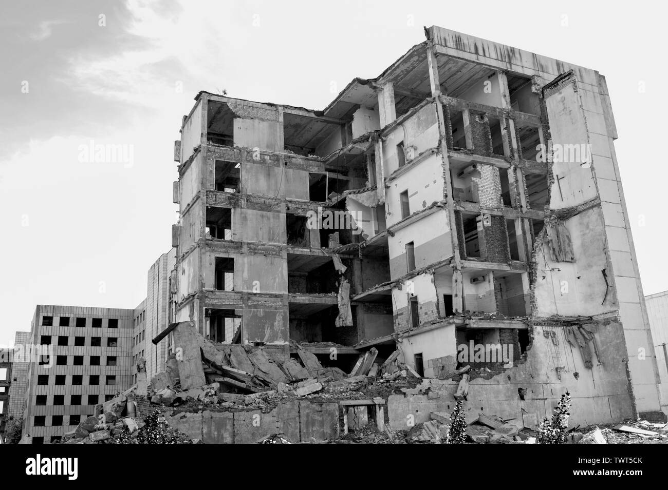 The remains of a destroyed concrete building against the sky. Black and ...