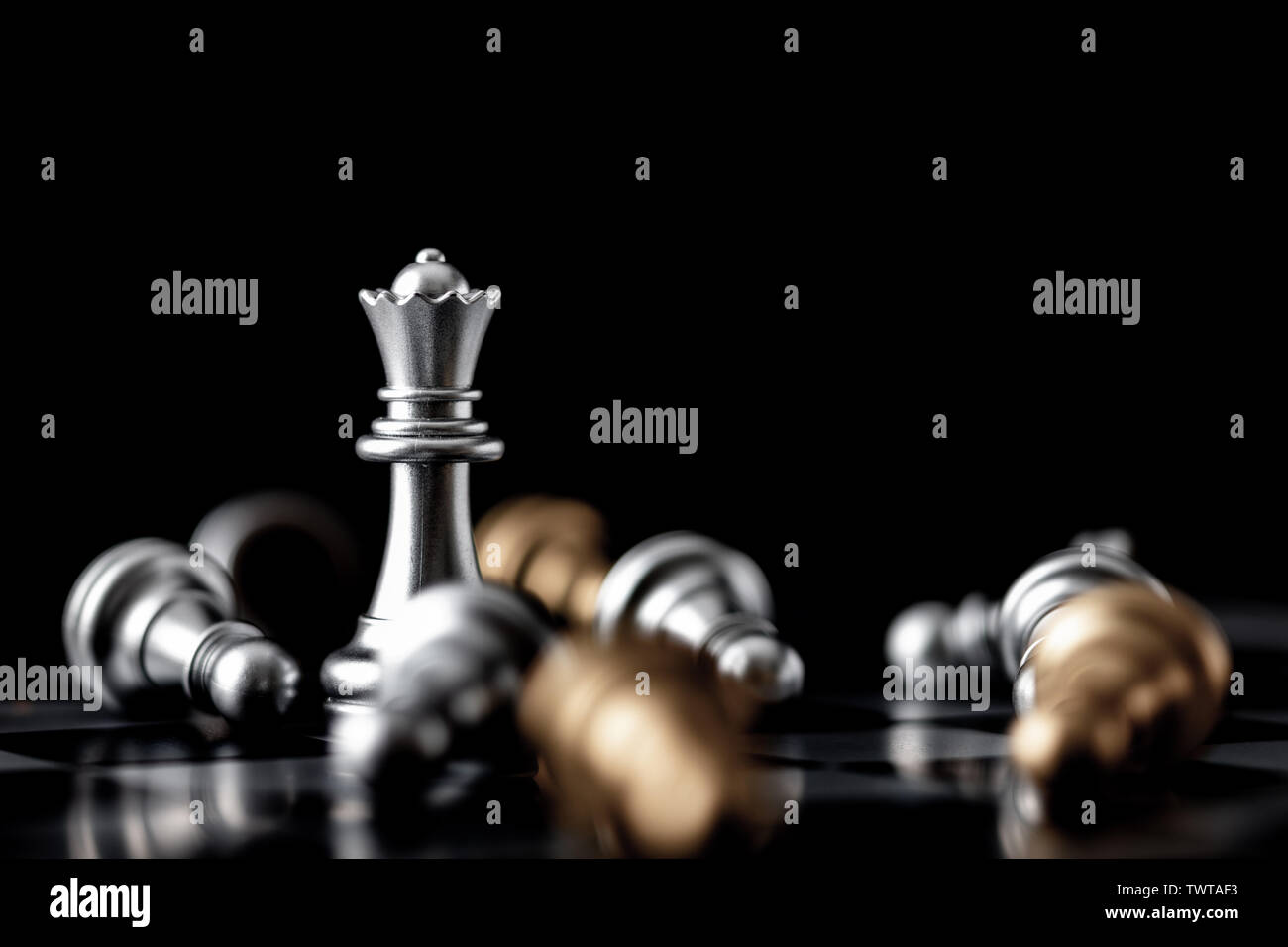 Queen standing in the midst of falling gold and silver chess on board ...