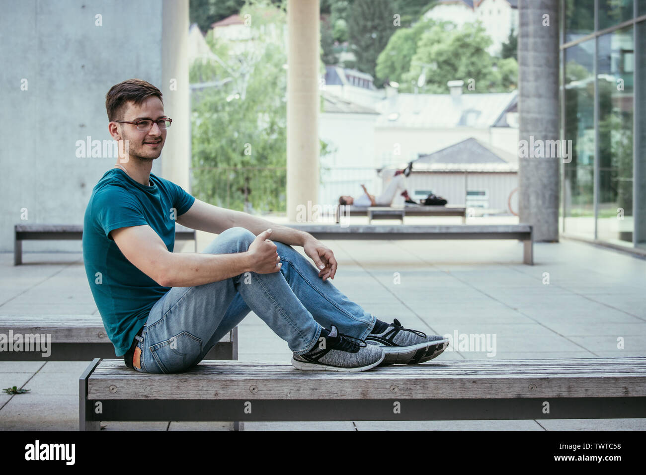 Male young employee is sitting outdoors, taking a break. Urban business ...
