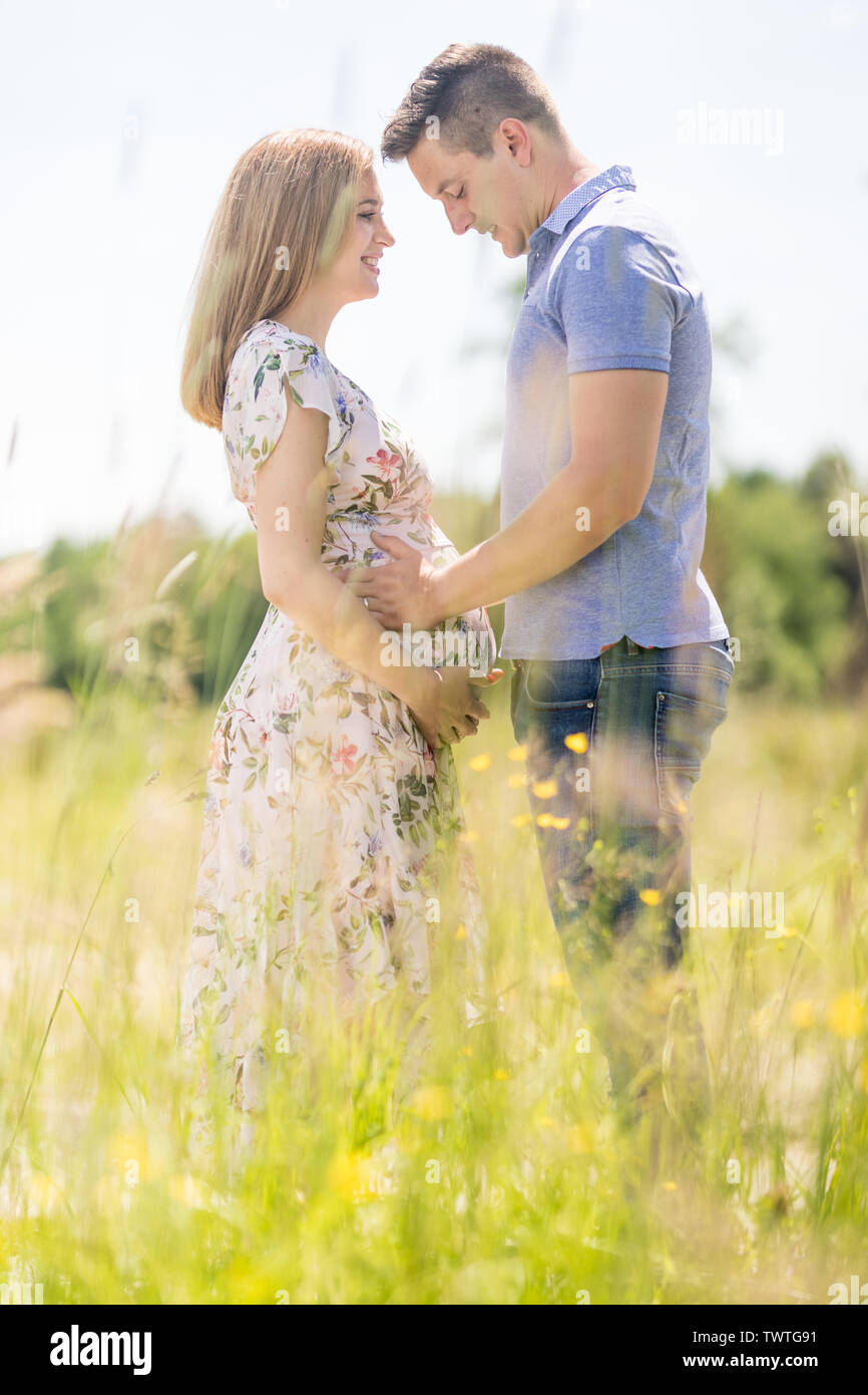 Young happy pregnant couple hugging in nature Stock Photo - Alamy