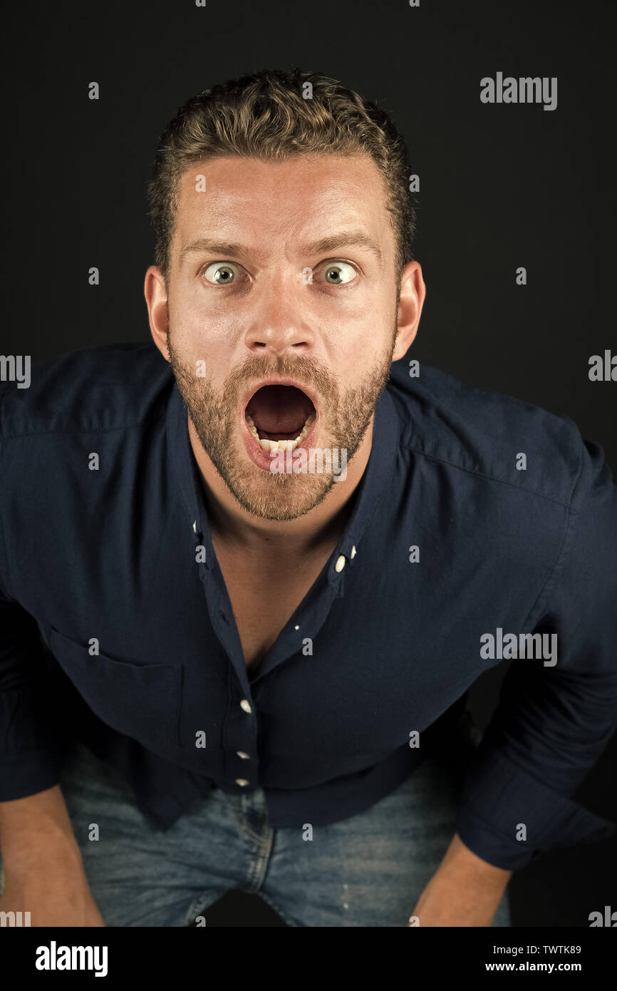 Man with open mouth on bearded face leaning forward on dark background ...