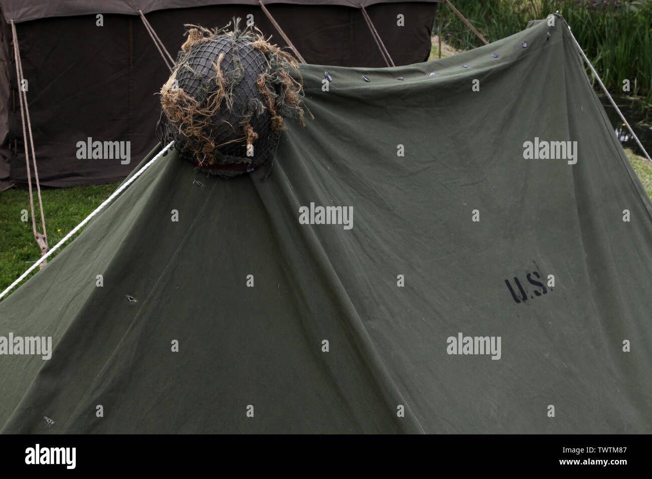 An American Army helmet with netting and camo hangs on a US Army tent ...