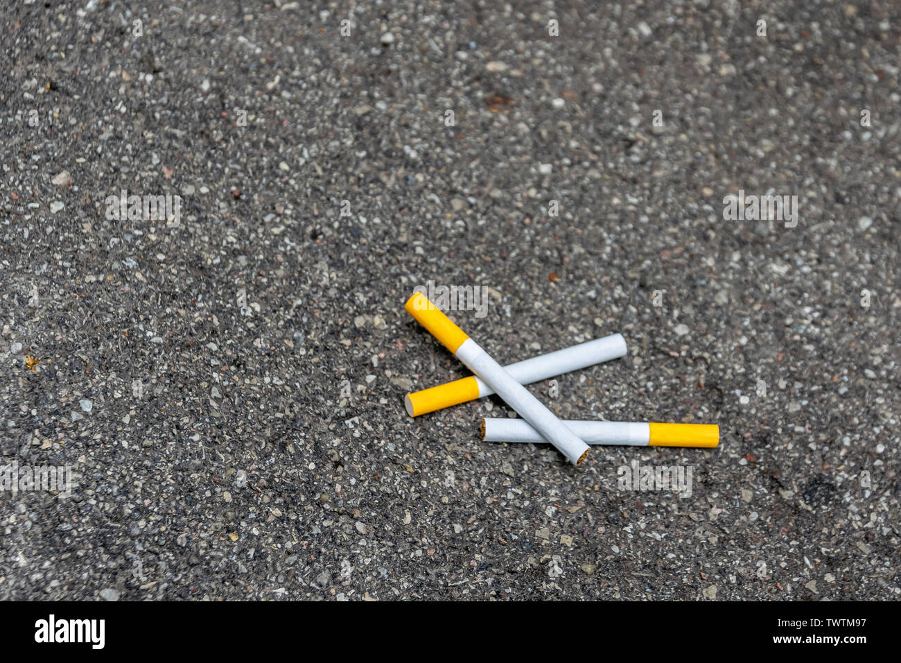 three cigarettes lying on the pavement Stock Photo - Alamy