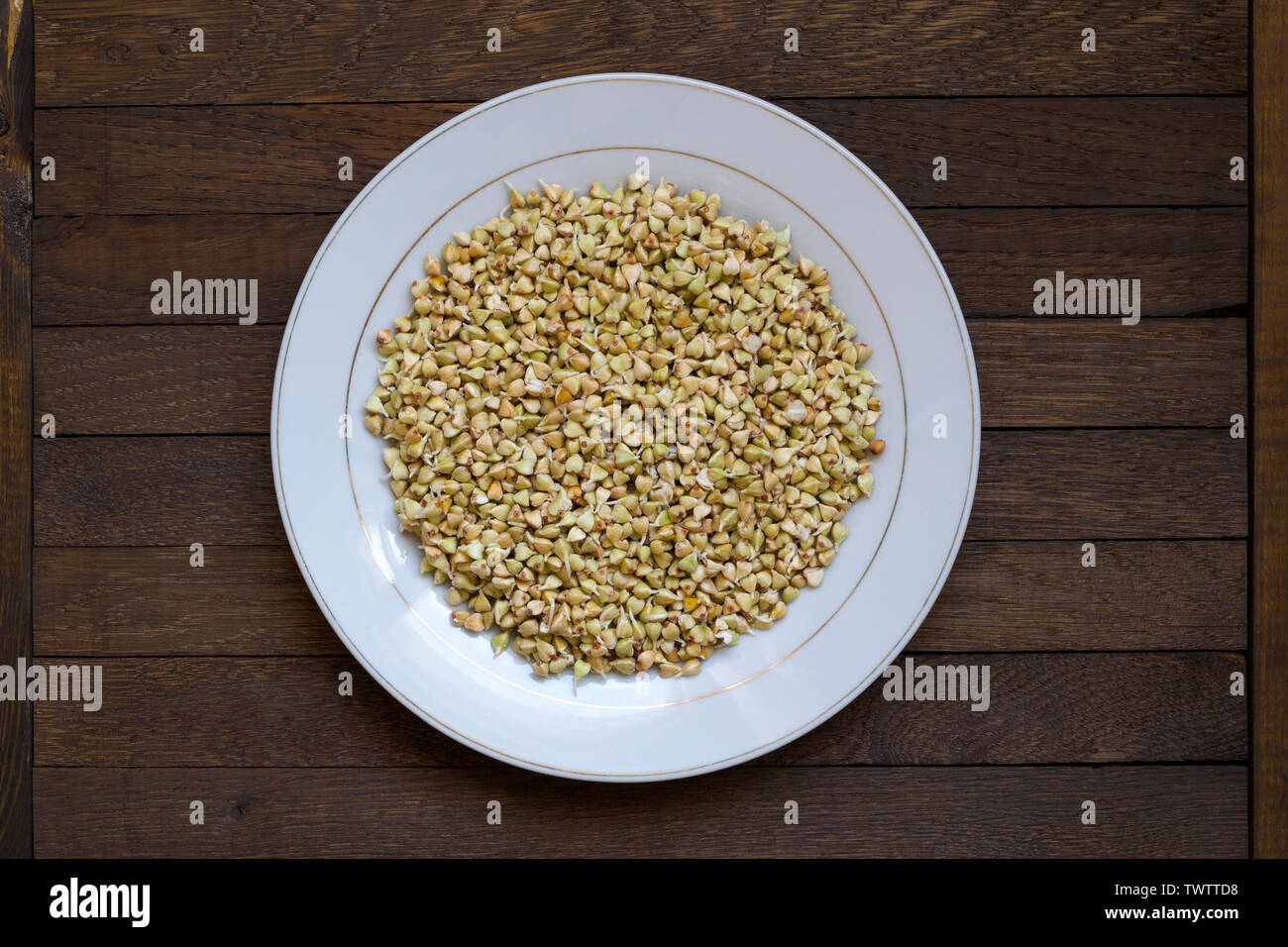 Sprouted buckwheat on white plate on brown wooden table. Top view ...