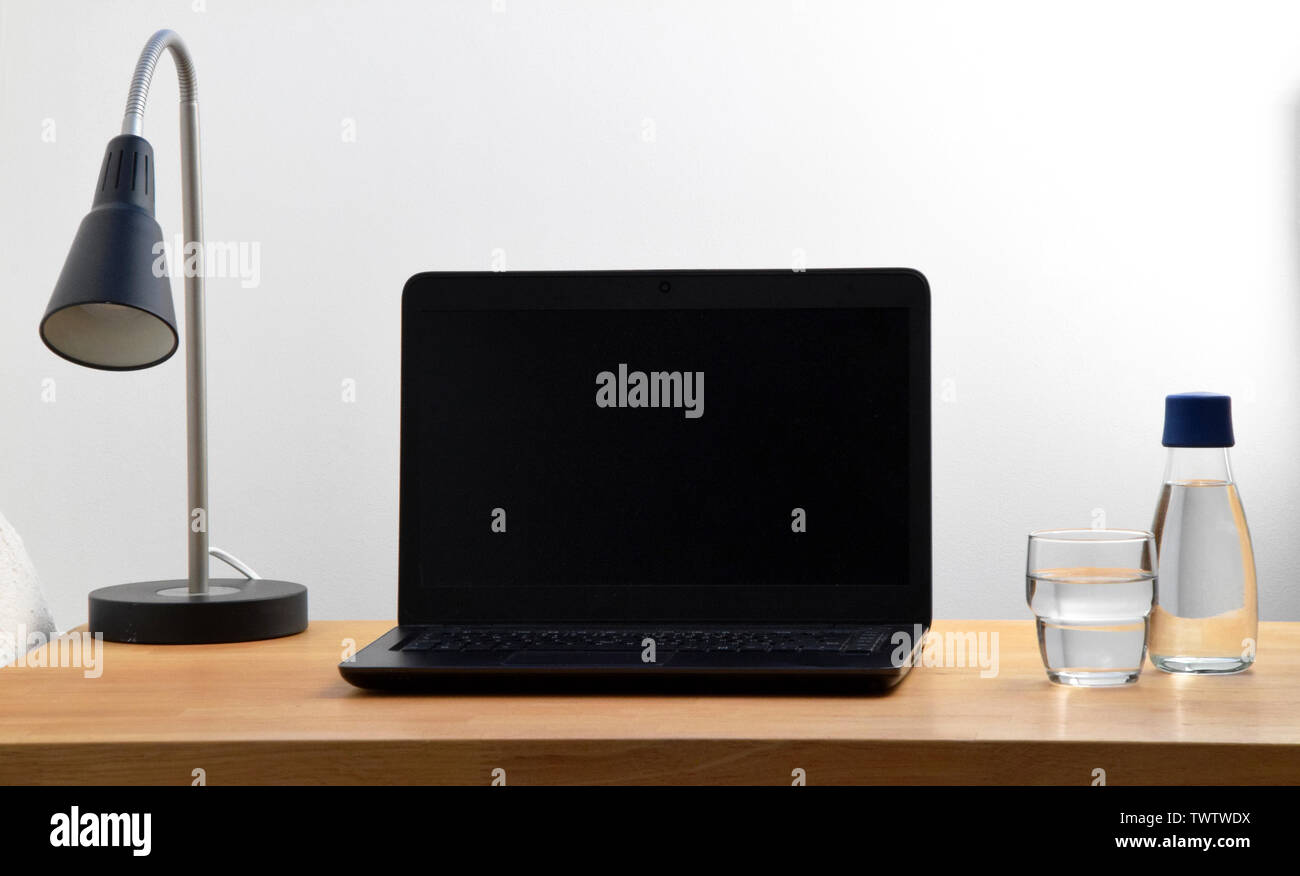 Home office with lamp, laptop, water bottle and glass of water on ...