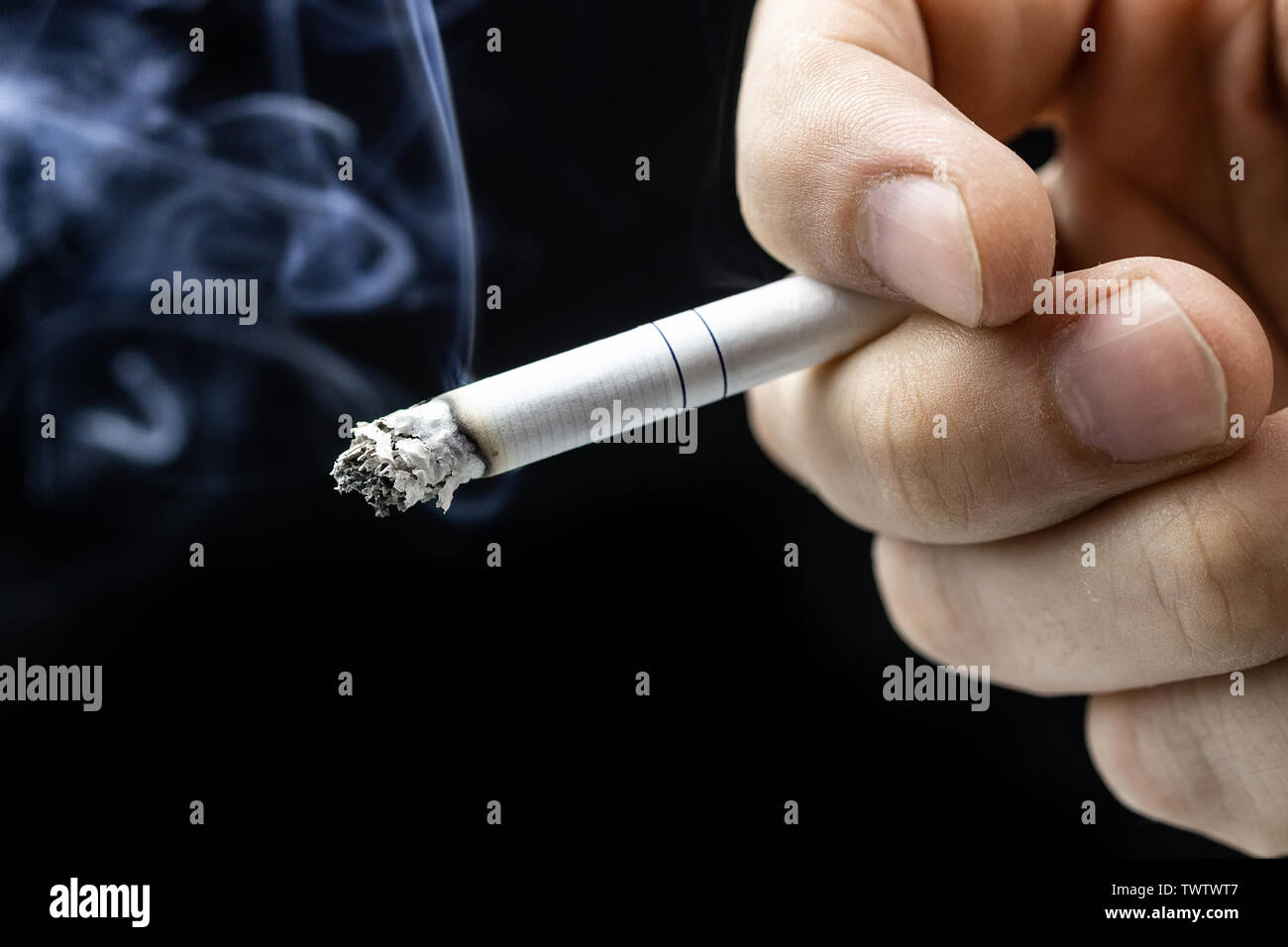 Hand with cigarette. White burning cigarette in the hands of a male ...