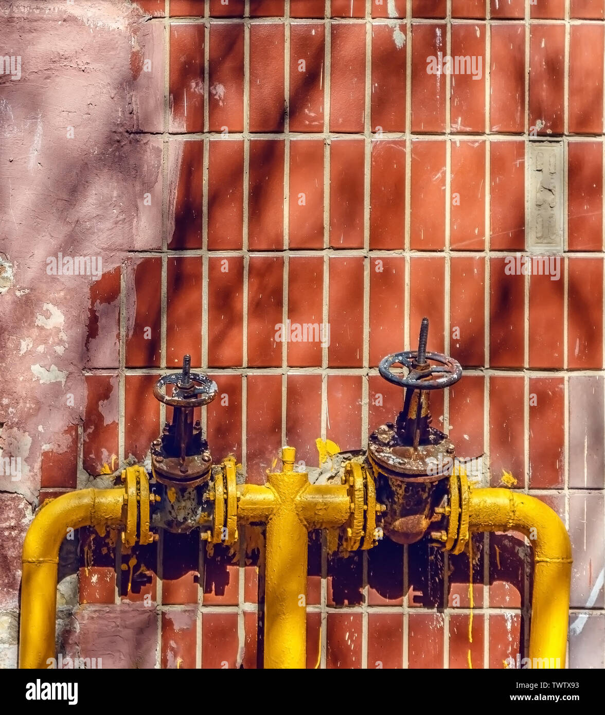 two yellow valves on the pipes on the wall of a tall building Stock ...