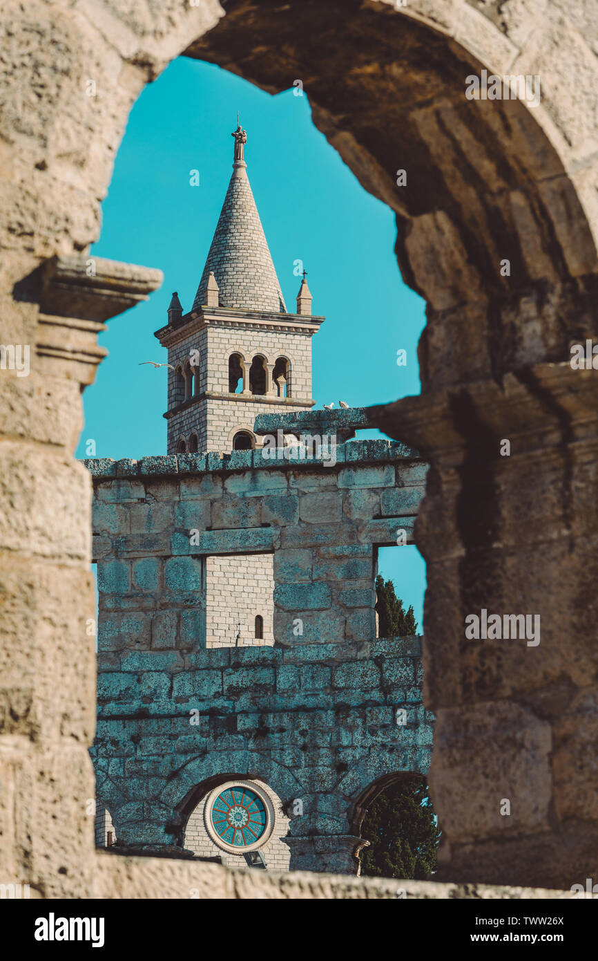 view of the church of pula through window of old roman coliseum in pula ...