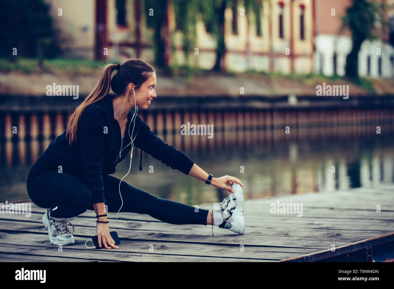 Young beautiful woman doing stretching exercises by the river Stock Photo - Alamy