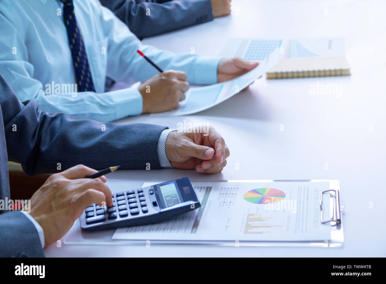 Businessmen in a meeting room are deeply reviewing financial statements ...
