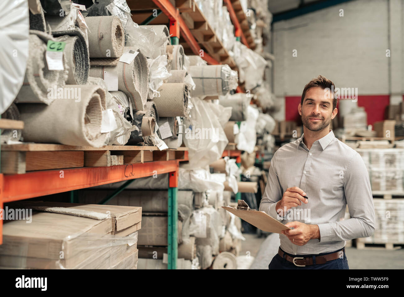 Smiling manager doing inventory on a warehouse floor Stock Photo - Alamy