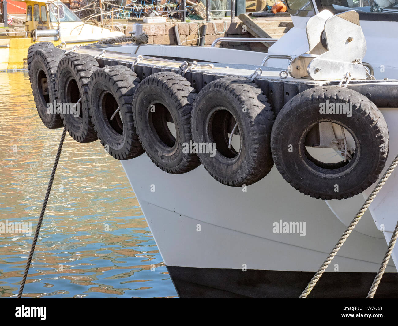 Detail of six black tyres on the outside of a white boat in the North ...