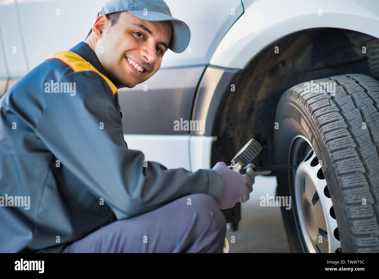 Smiling mechanic inflating a van's tire Stock Photo - Alamy