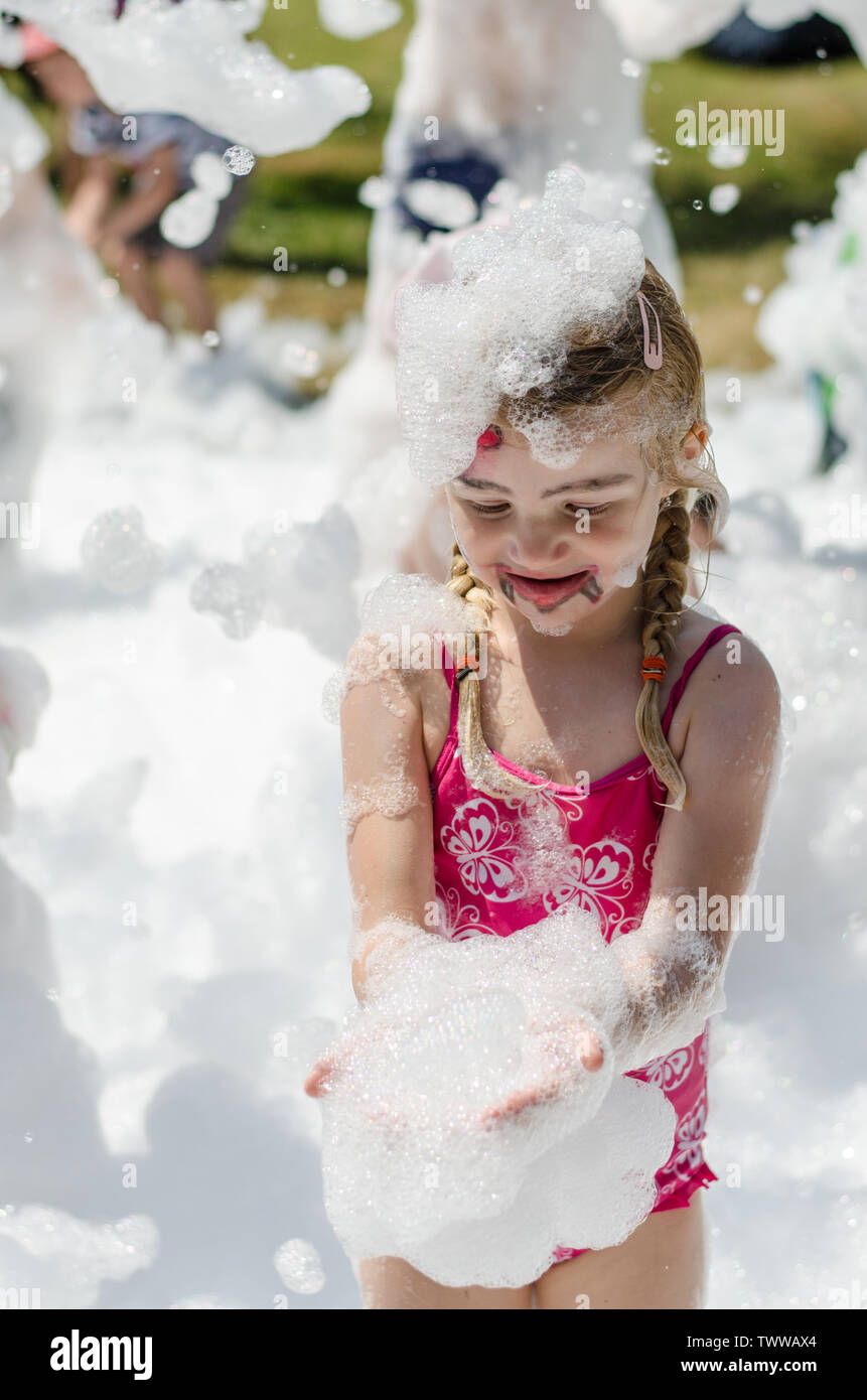 smiling blond girl enjoying foam party Stock Photo - Alamy