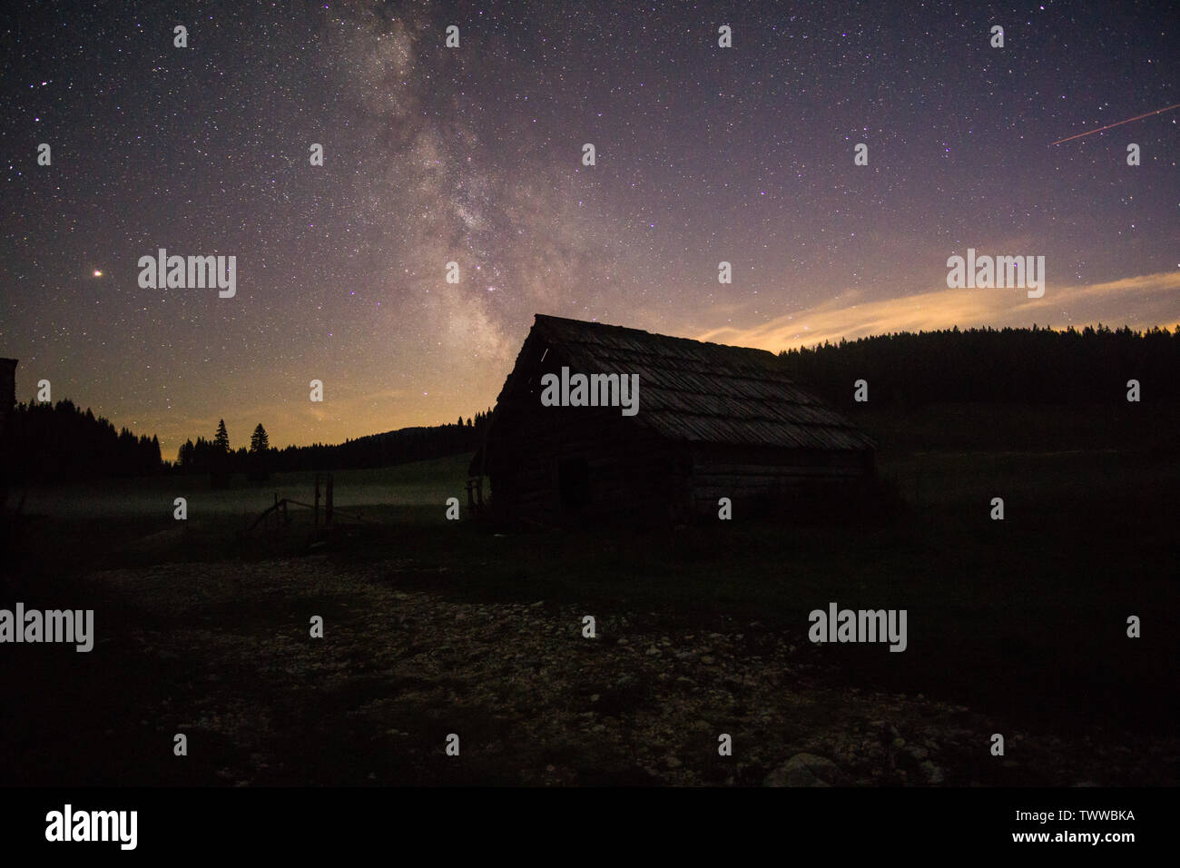 purple night sky stars over mountain and old wooden house. Milky way ...