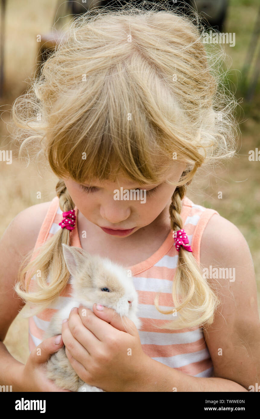 beautiful blond girl holding young bunny rabbit Stock Photo - Alamy