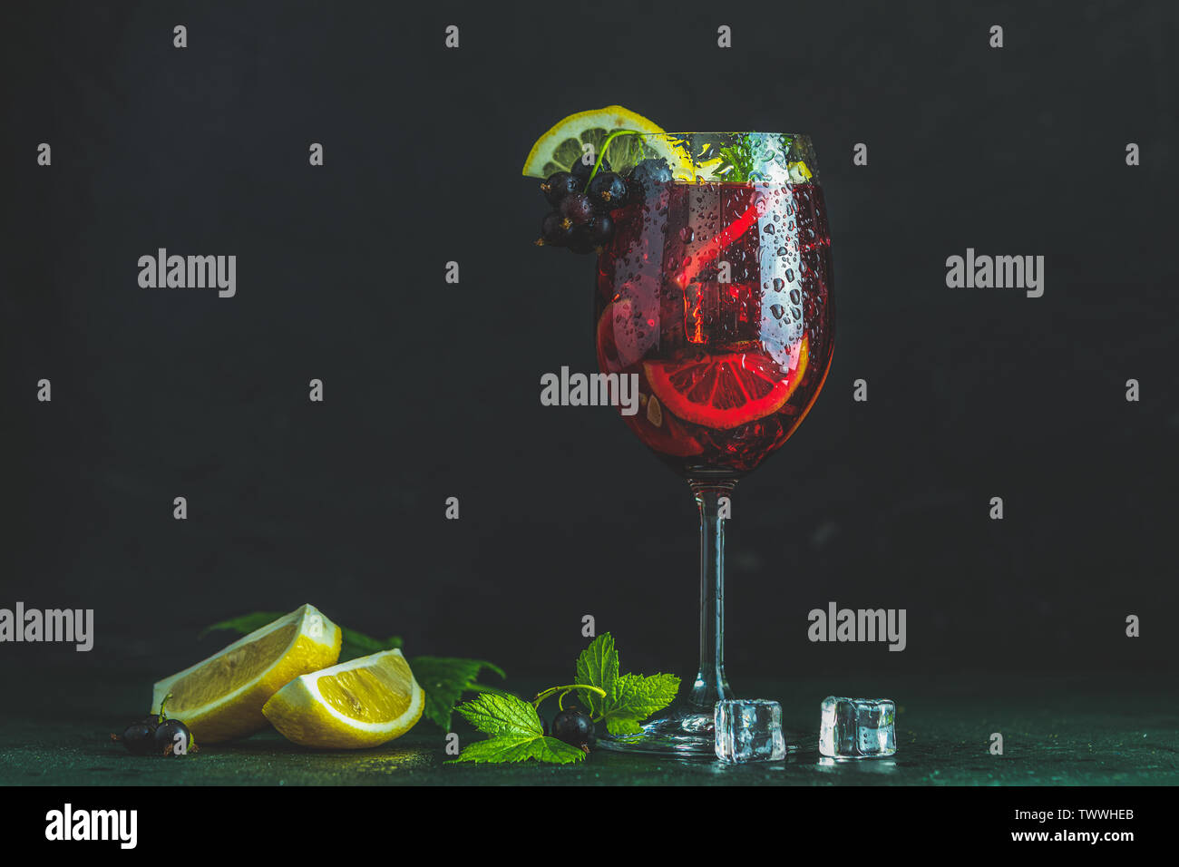 Cold red cocktail with blackcurrant, lemon, mint and ice in tall glass ...