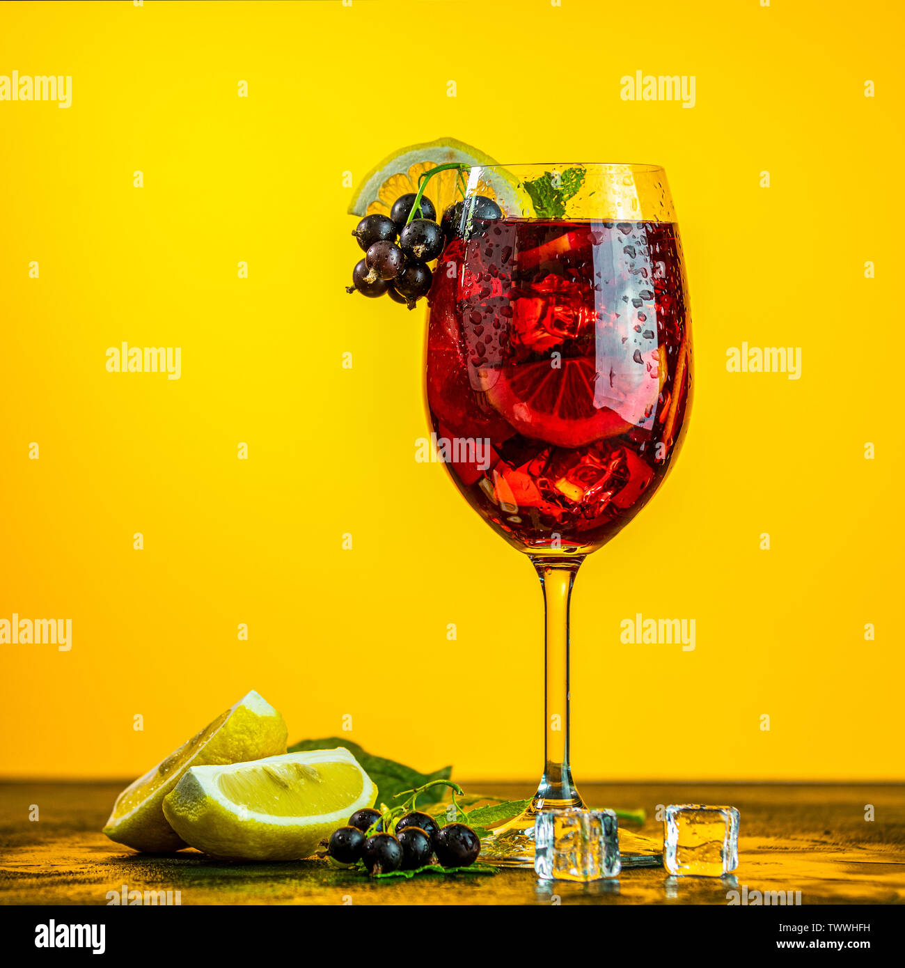 Cold red cocktail with blackcurrant, lemon, mint and ice in tall glass ...