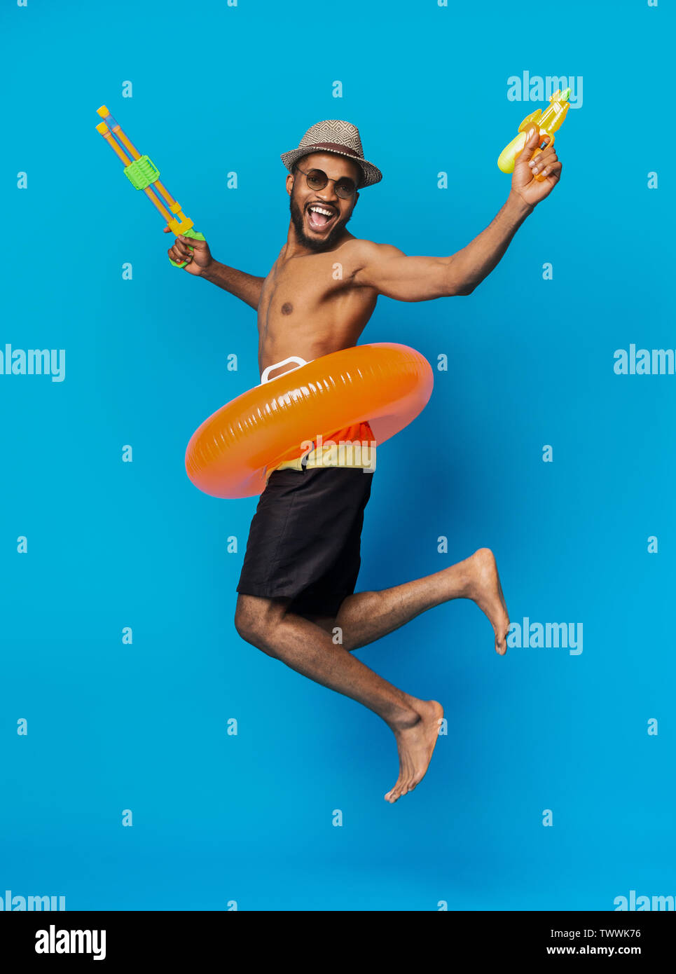 Playful black man jumping with water guns Stock Photo - Alamy