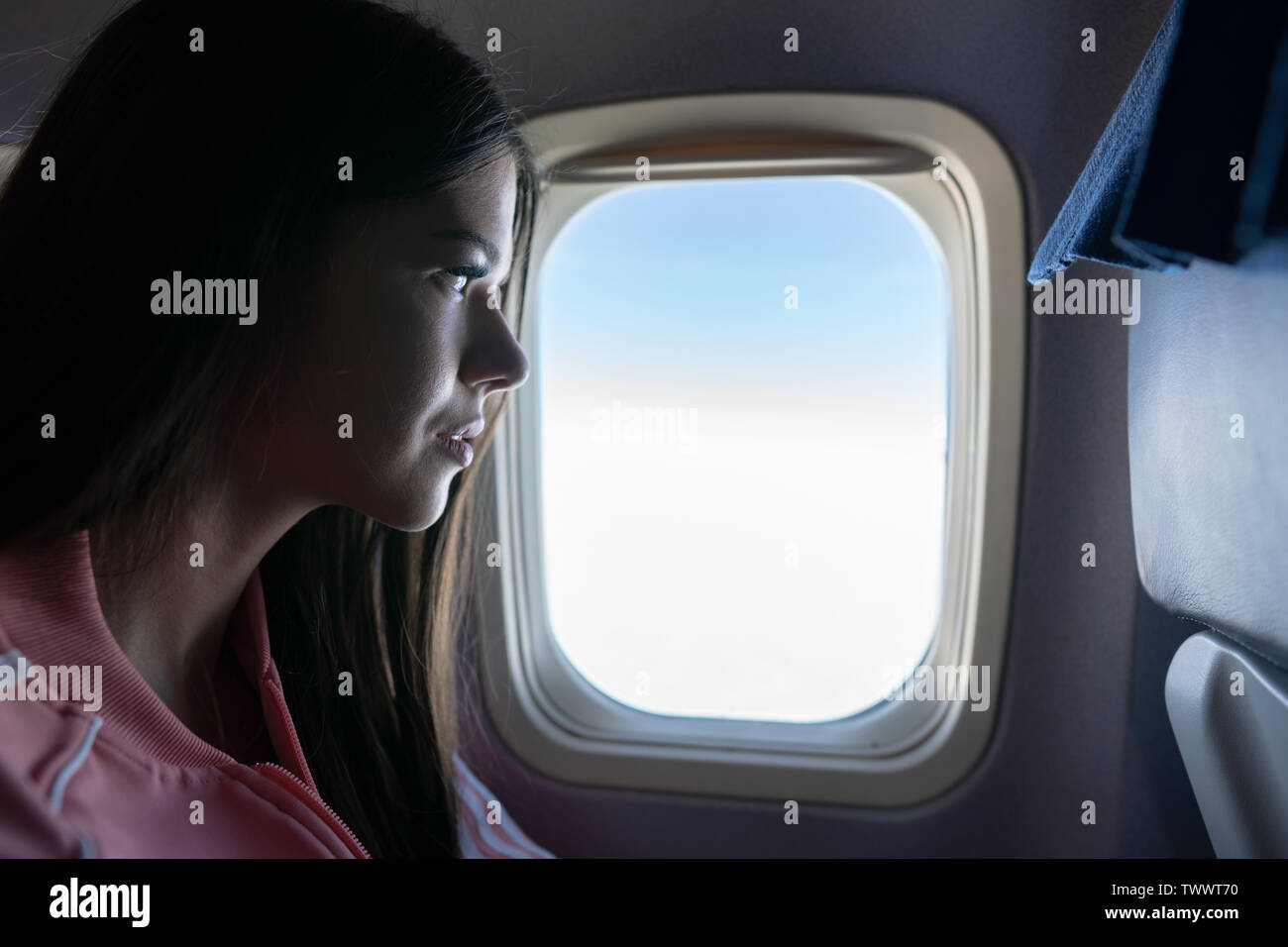 Young woman looking through window in the airplane Stock Photo - Alamy