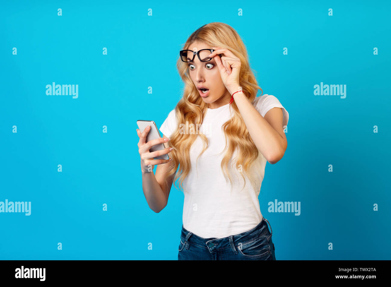 Shock Content. Woman Looking At Smartphone In Studio Stock Photo - Alamy